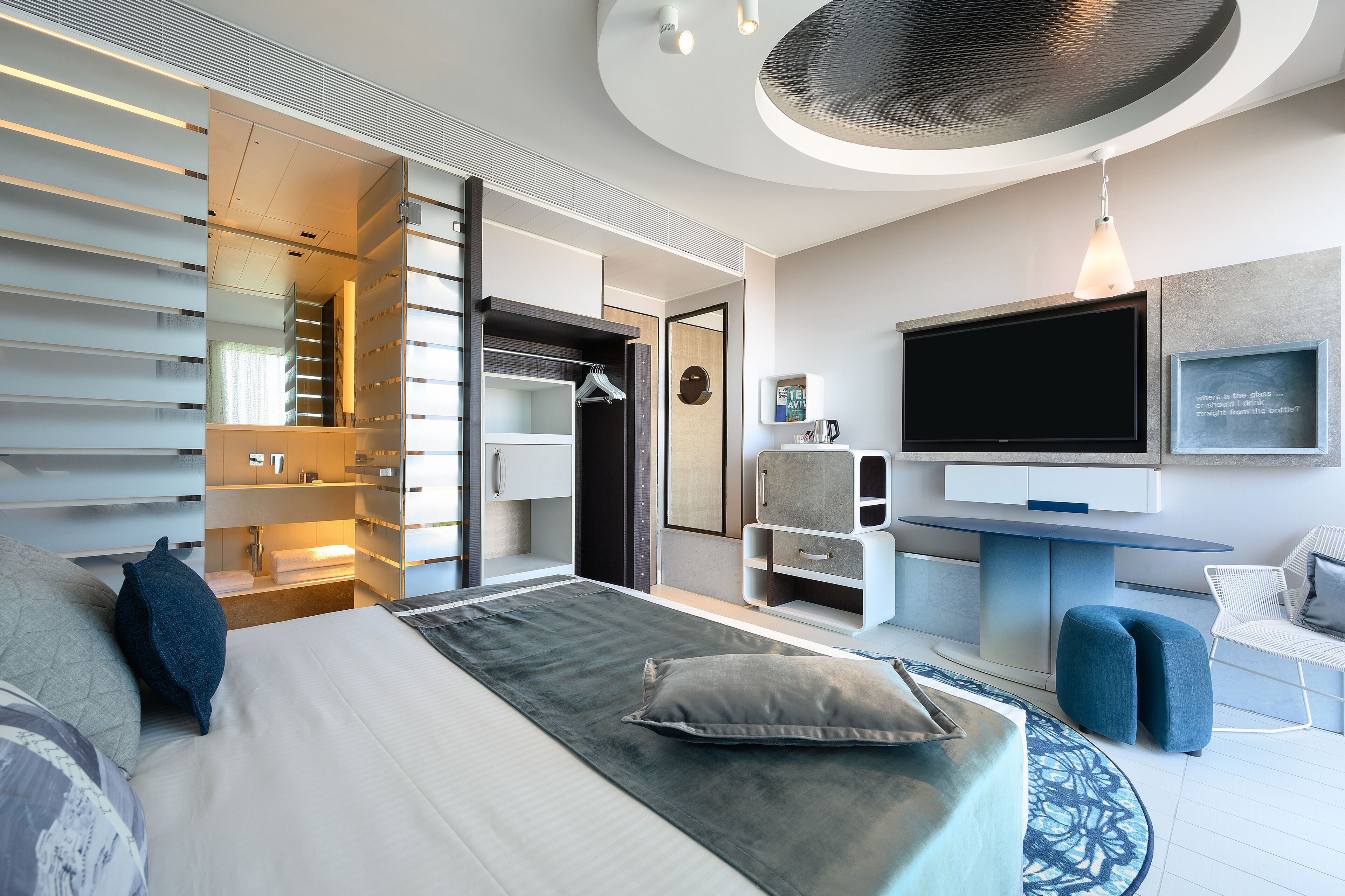 Quarto de hotel moderno com cama, televisão, escrivaninha e closet espaçoso.