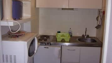 Uma cozinha compacta com micro-ondas, mini-geladeira, pia e fogão.