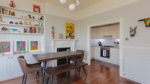 Uma cozinha moderna com armários brancos, uma ilha central e um espaço de jantar com mesa e cadeiras de madeira.