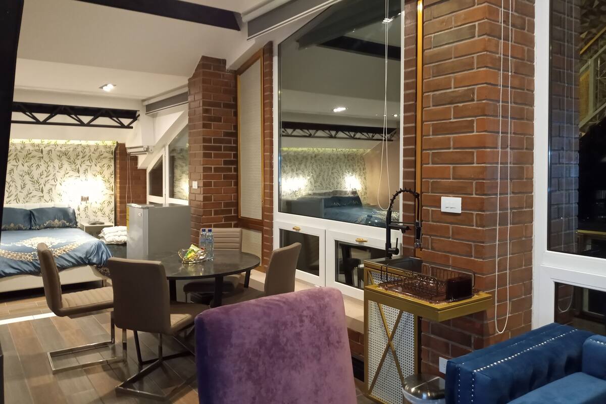 Uma sala de estar moderna com área de jantar, uma janela grande e uma parede de tijolos.
