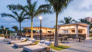 Resort com área de estar ao ar livre, palmeiras e bar.