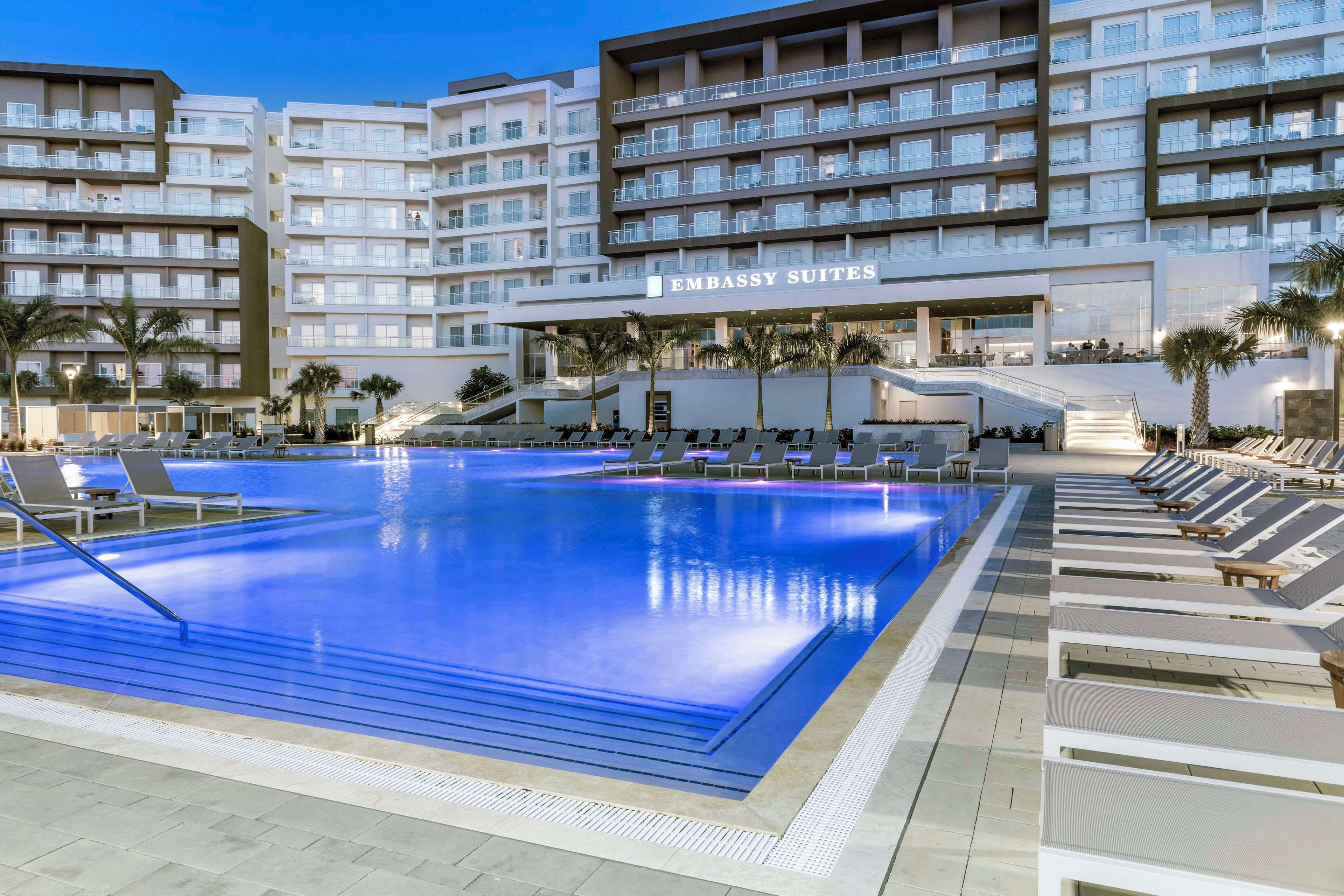 Um hotel com piscina, espreguiçadeiras e uma placa com a inscrição 'Embassy Suites'.