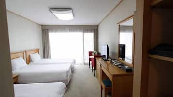 Quarto de hotel com duas camas, uma escrivaninha com computador e um espelho grande.