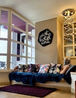 Quarto com sofá, um letreiro decorativo, janela e lustre.