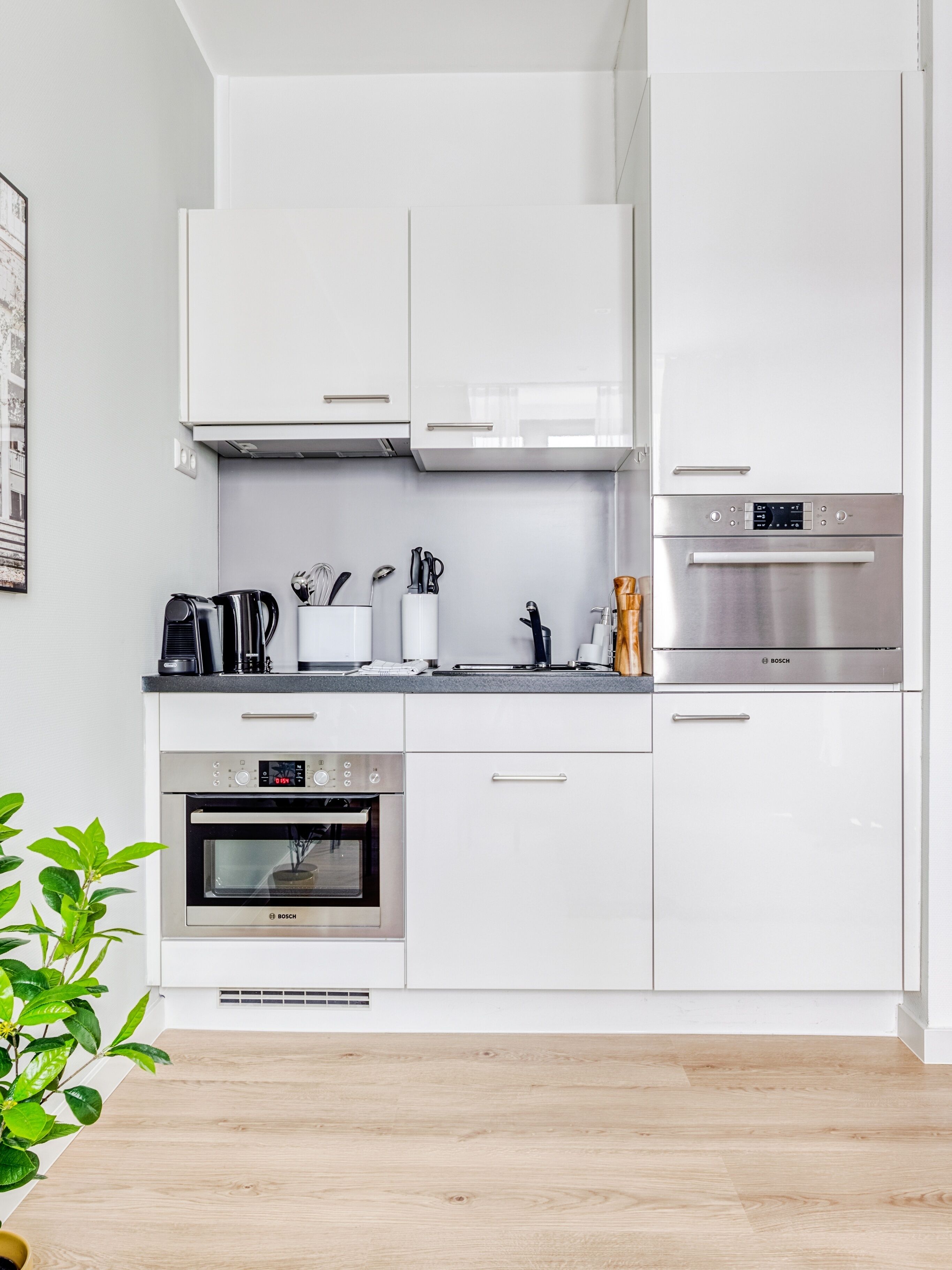 Cozinha moderna com armários brancos, forno Bosch e cafeteira.