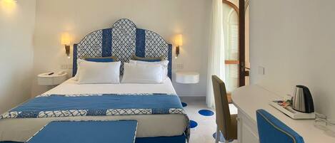 Quarto de hotel com cama, mesas de cabeceira, escrivaninha e cadeira.