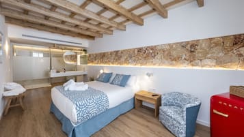 Quarto moderno com uma cama grande, mesa de cabeceira, uma cadeira e uma mala vermelha.