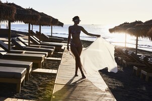 Na praia, areia preta, barracas de praia de cortesia, espreguiçadeiras 
