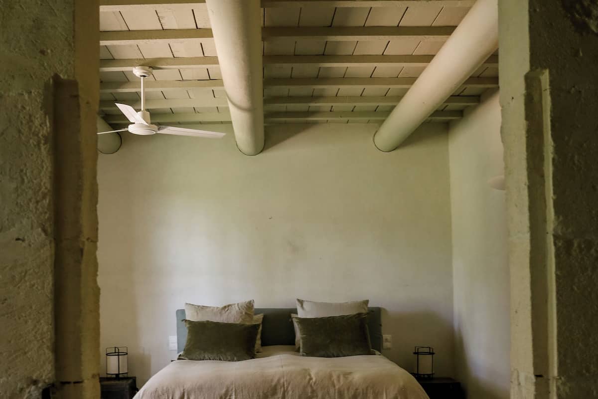 Quarto com cama, duas mesas de cabeceira e ventilador de teto.