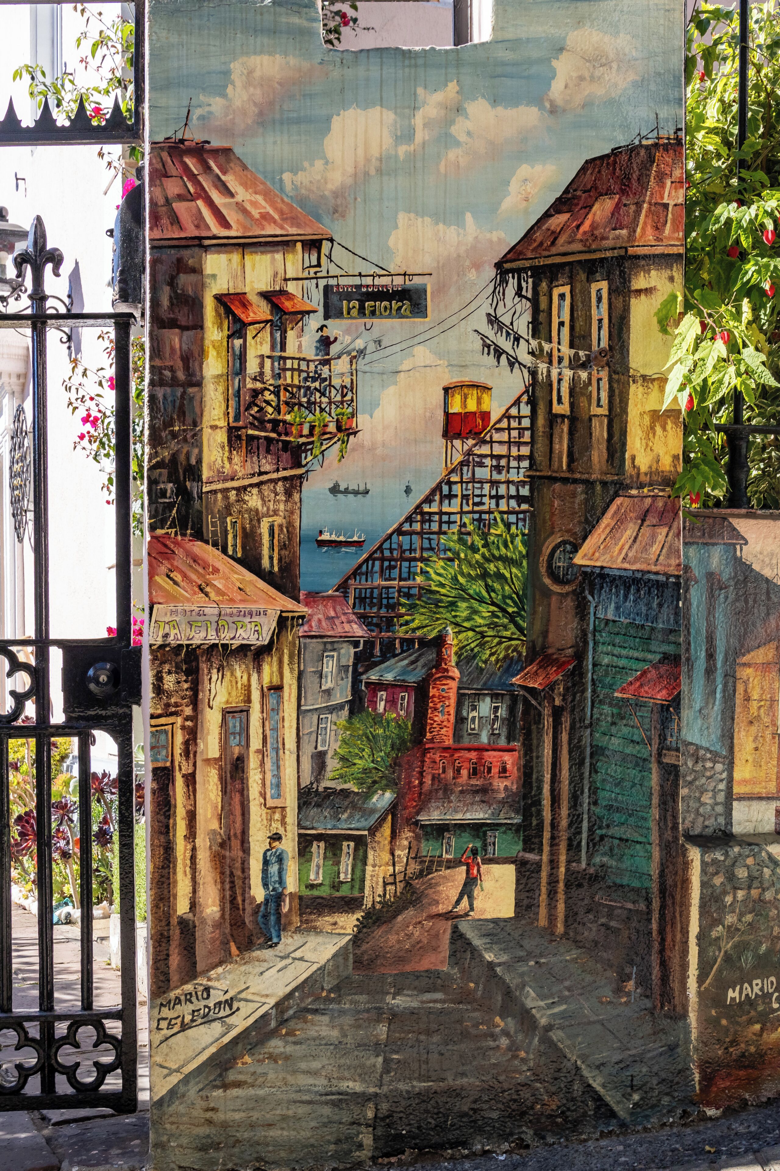 Um mural retrata uma rua estreita com edifícios, uma escadaria e uma pessoa caminhando.