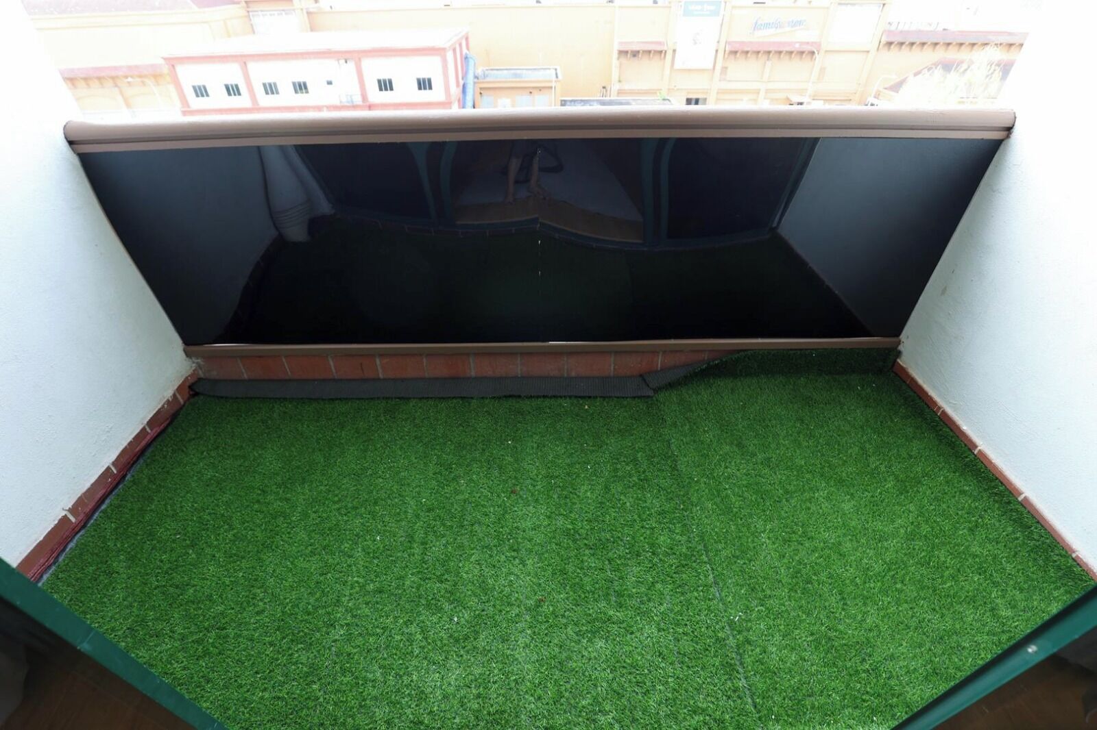 Quarto com piso de grama sintética verde e teto preto.