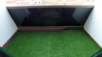 Quarto com piso de grama sintética verde e teto preto.