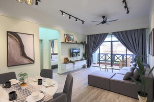 Uma sala de estar moderna com área de jantar, sofá, televisão e varanda com cortinas.