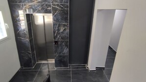 Elevador moderno com paredes de mármore e interior metálico.