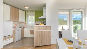 Uma cozinha moderna com armários brancos e de madeira, uma máquina de lavar louça e um espaço de refeições com uma mesa posta para dois.