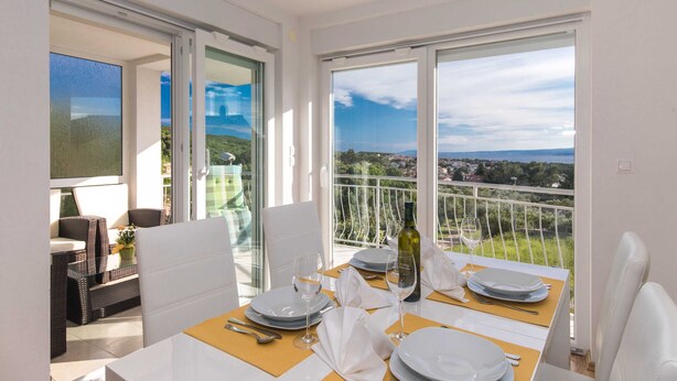 Espaço de refeições com uma mesa posta para quatro, com vista panorâmica.