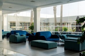 Um hall espaçoso com mobiliário moderno, janelas amplas e vista do interior do edifício.