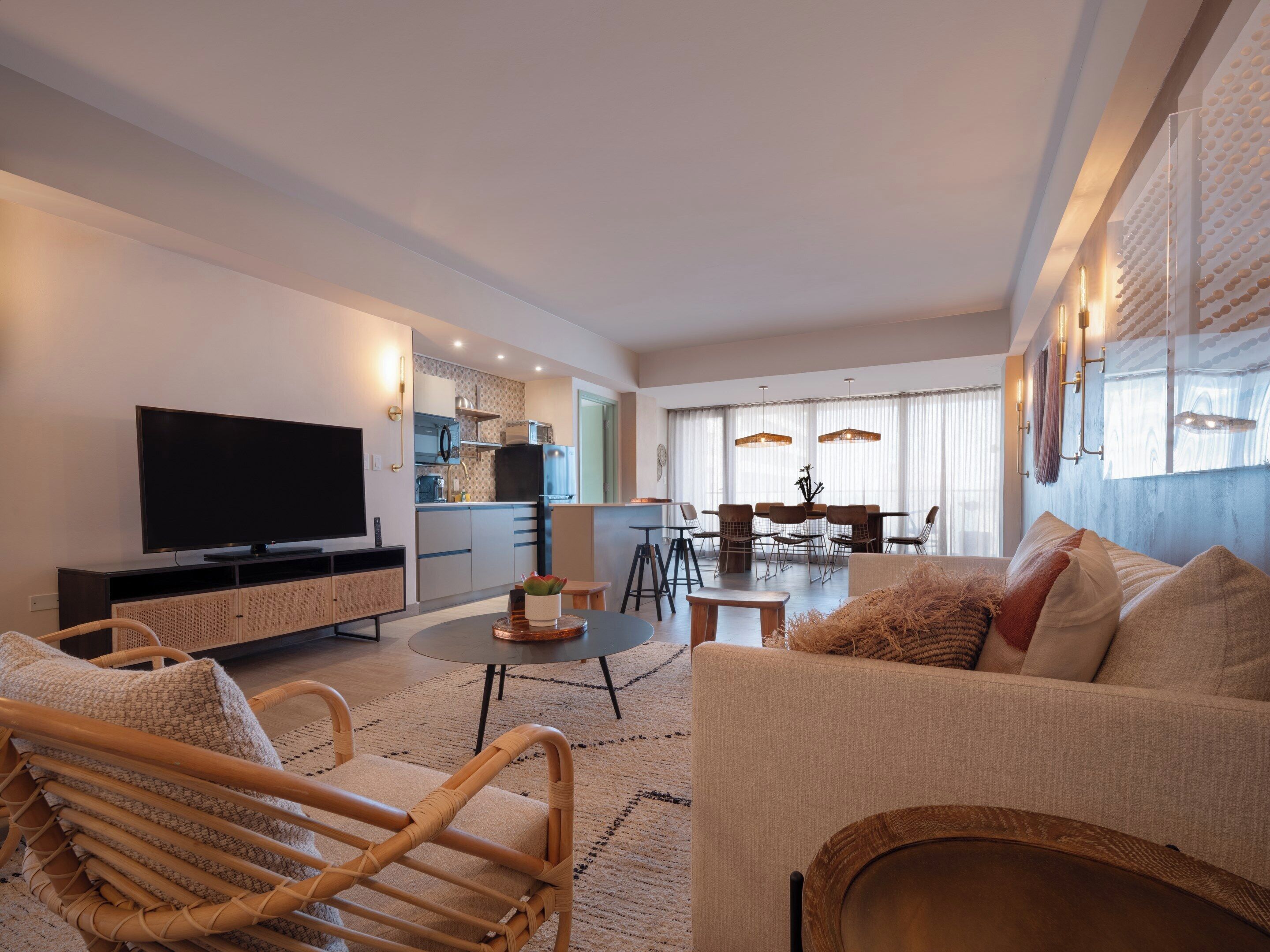 Sala de estar moderna com televisão, sofá e área de jantar.