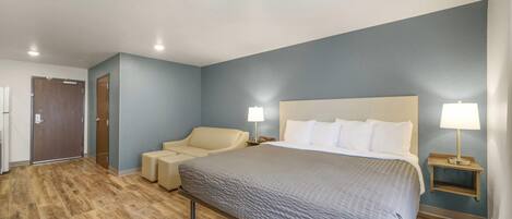Quarto de hotel com uma cama grande, um sofá, uma escrivaninha e uma porta.