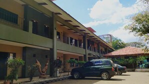 Um edifício de vários andares com fachada verde, varandas e um carro estacionado.