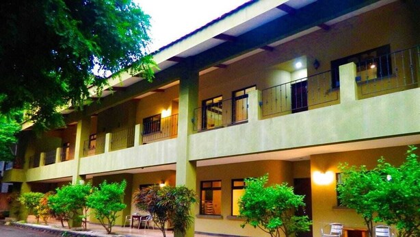 Um hotel com vários andares, varandas, área de estar ao ar livre e paisagismo bem cuidado.
