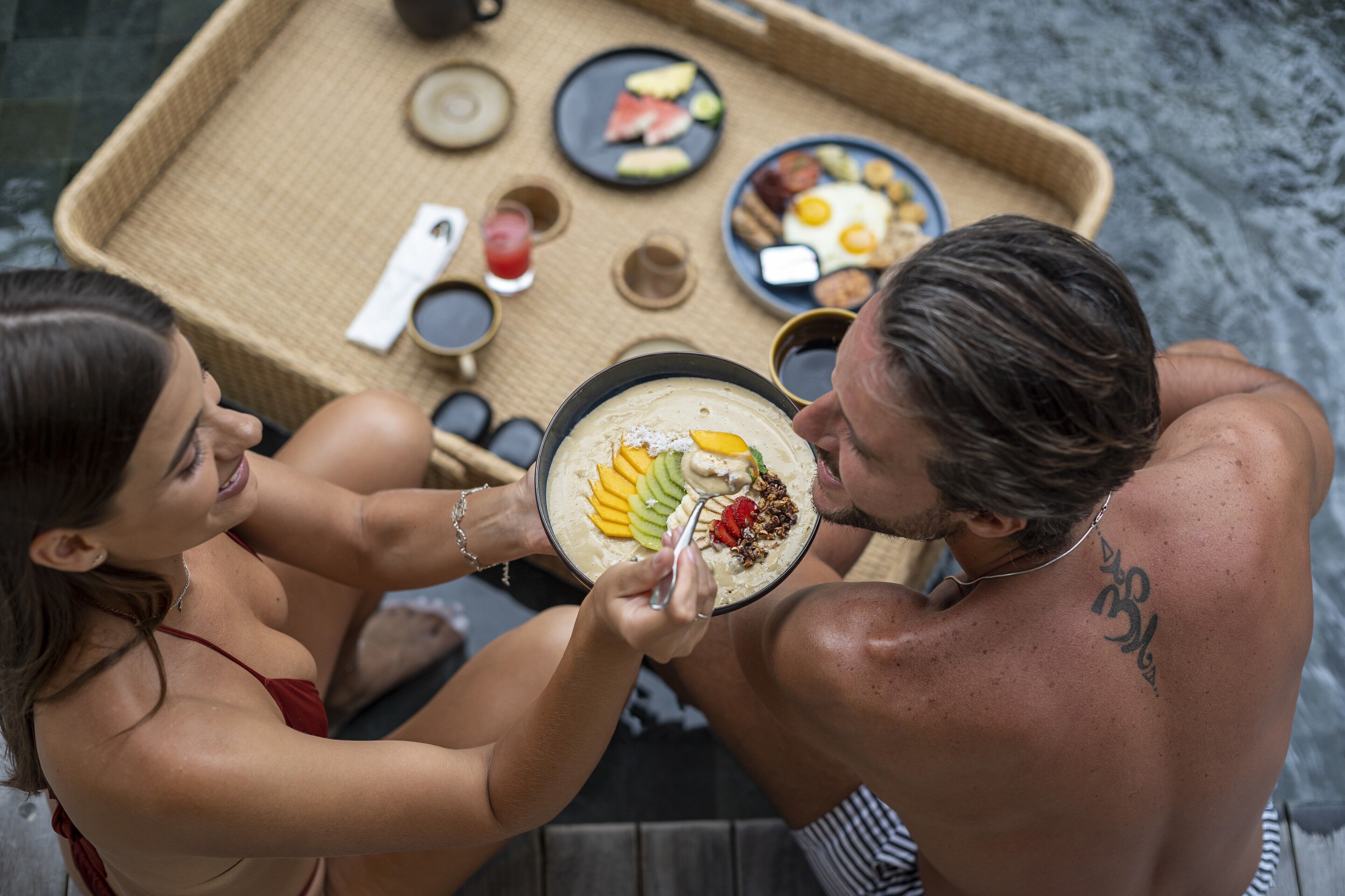 Um casal desfrutando de uma refeição juntos, com uma bandeja contendo vários pratos e bebidas.
