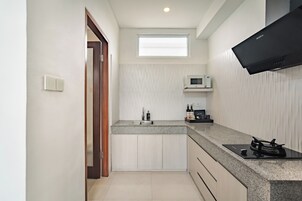Cozinha moderna com micro-ondas embutido, fogão a gás e uma pequena janela sobre a pia.