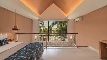 Quarto moderno com uma cama grande, escrivaninha e varanda com vista para palmeiras.