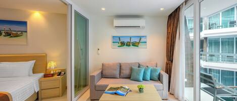 Quarto de hotel moderno com cama, sofá, mesa e varanda com vista.