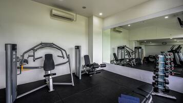 Uma academia com diversos equipamentos de exercício, incluindo um suporte para agachamento, banco de supino e halteres.
