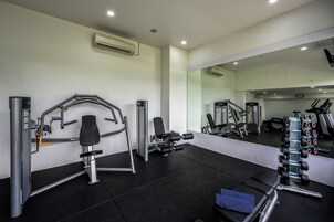 Uma academia com diversos equipamentos de exercício, incluindo um suporte para agachamento, banco de supino e halteres.
