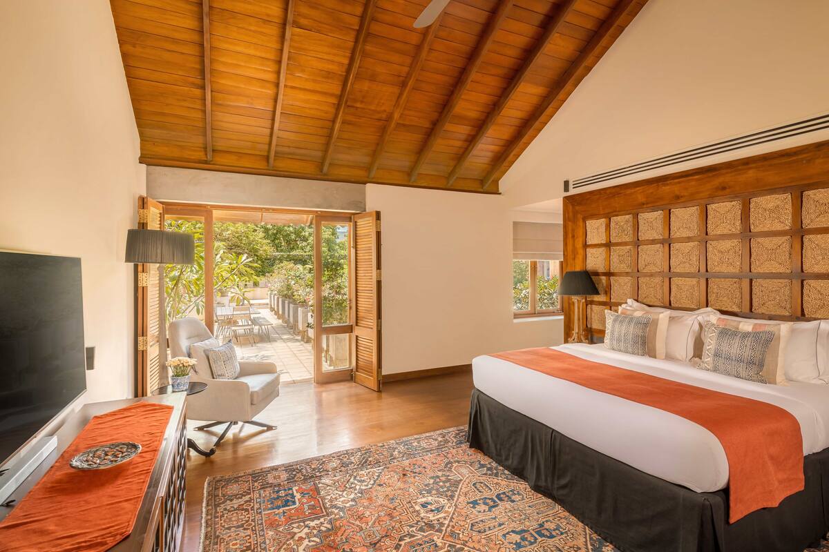 Quarto com uma cama grande, televisão e vista para o exterior.