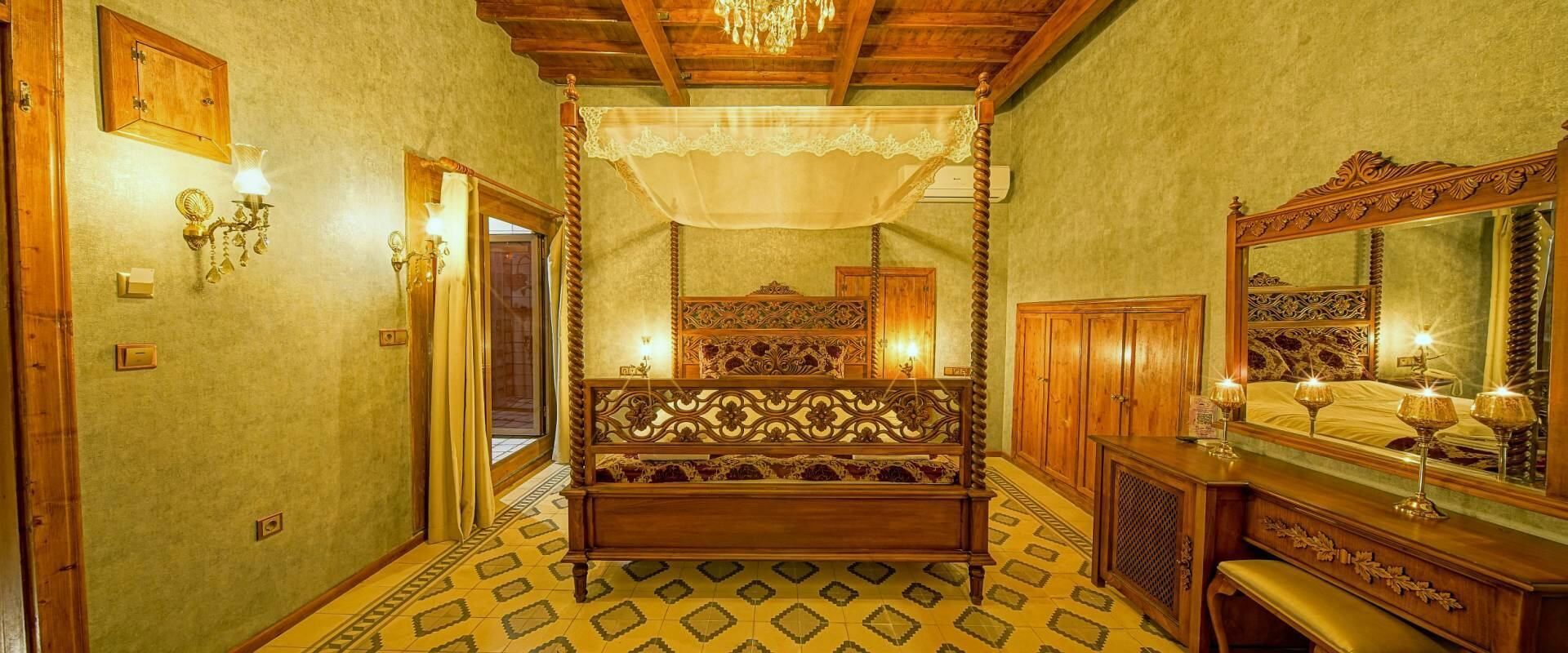 Quarto tradicional com cama de dossel, móveis de madeira e um espelho grande.
