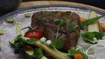 Prato com bife, legumes e uma pequena tigela ao fundo.
