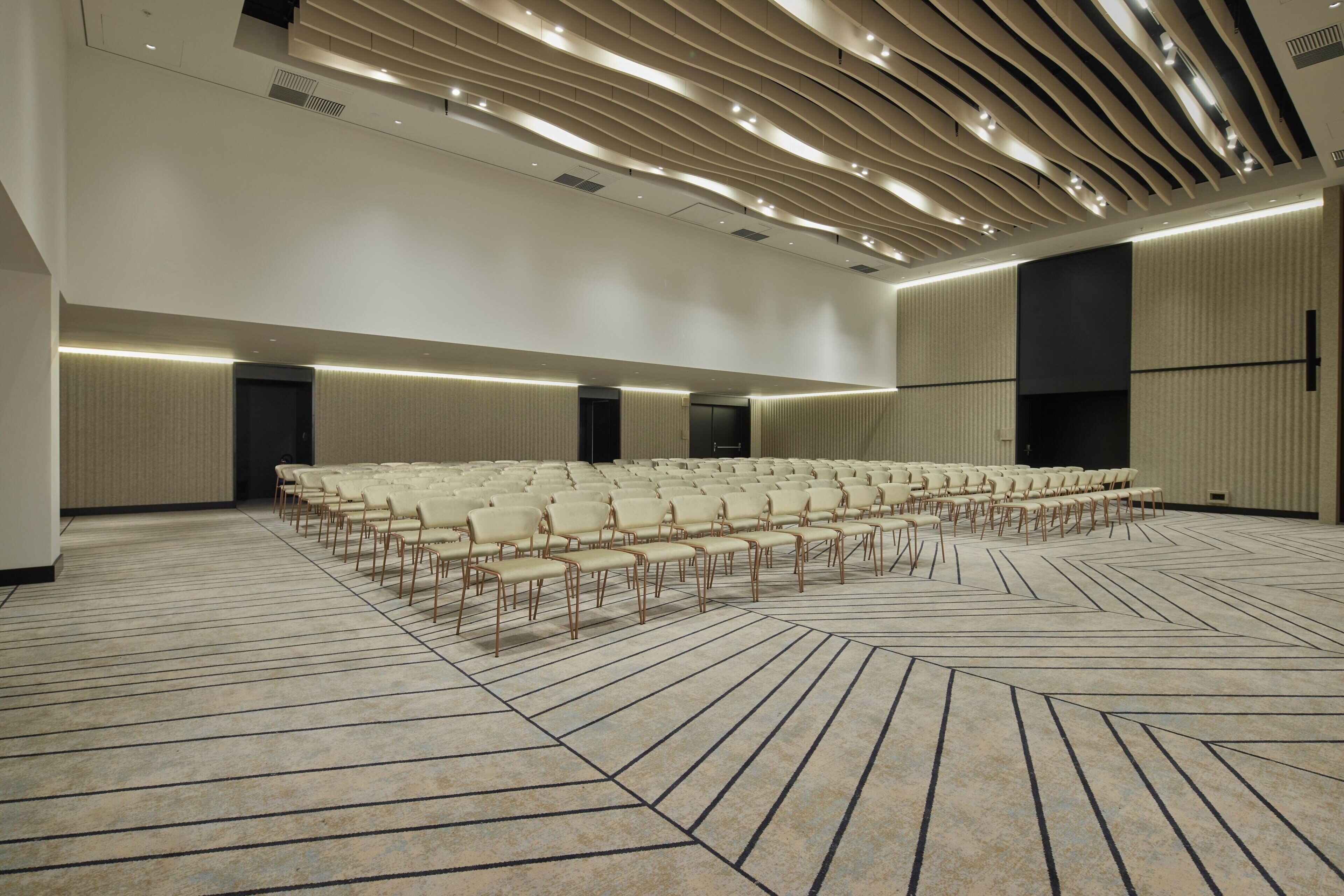 Uma sala de conferências ampla e moderna, com fileiras de cadeiras e piso estampado.
