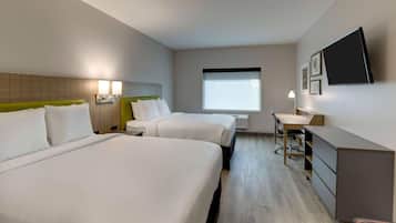 Quarto de hotel com duas camas, uma escrivaninha, uma cadeira, uma televisão e uma janela.