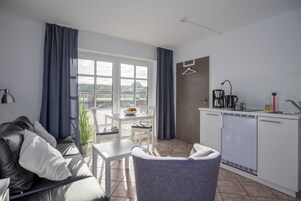 Uma sala de estar moderna com sofá, mesa de jantar e área de cozinha com pia e cafeteira.