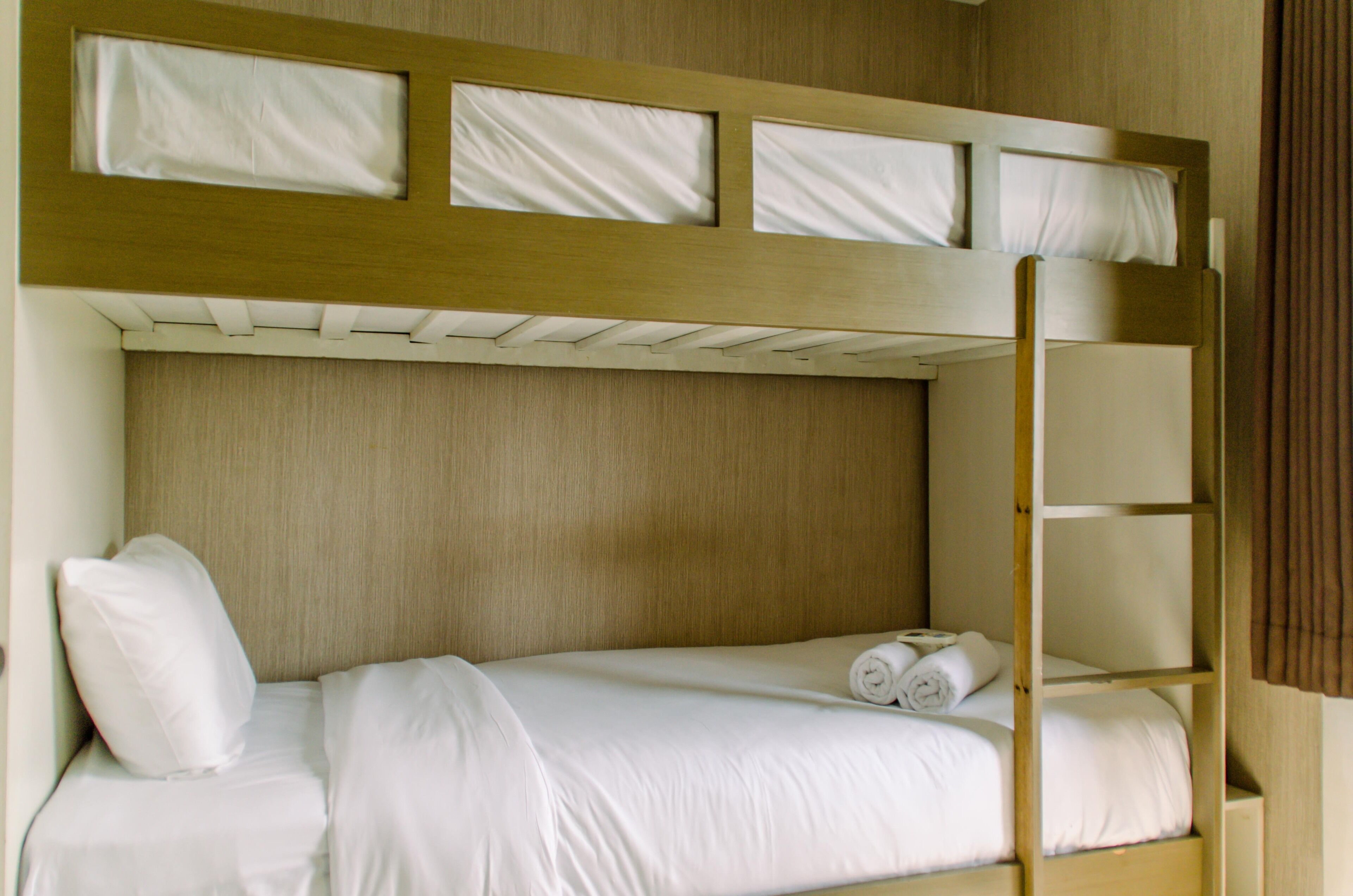 Uma cama beliche com cabeceira de madeira, roupa de cama branca e uma escada no lado direito.