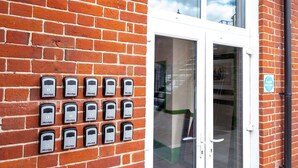 Um edifício de tijolos com porta de vidro e uma fileira de caixas de correio numeradas na parede.