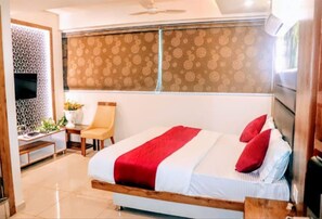 Quarto de hotel moderno com uma cama grande, uma escrivaninha, uma cadeira e uma televisão.