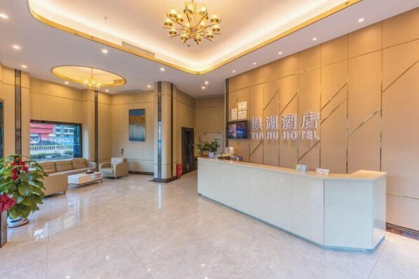 Um lobby de hotel moderno com balcão de recepção, área de estar e uma tela grande.