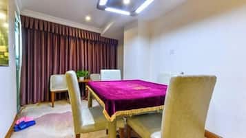 Uma sala de jantar com uma mesa coberta por um tecido roxo, quatro cadeiras e um lustre.