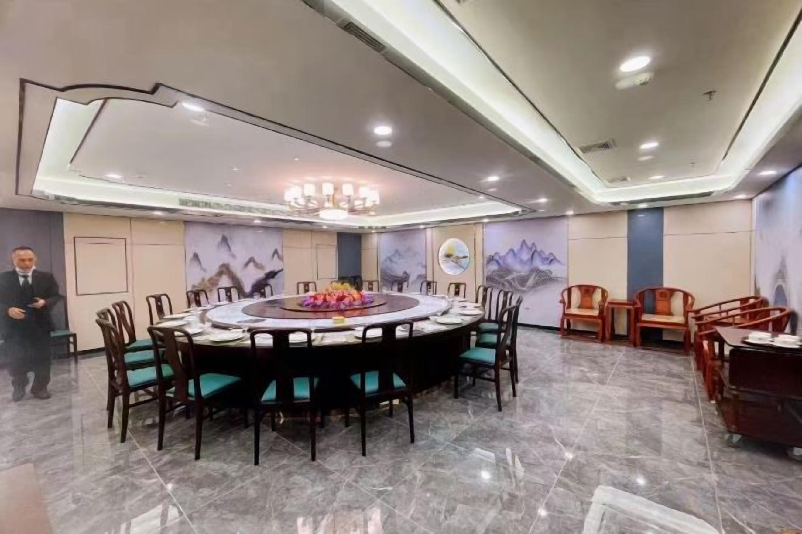 Uma sala de conferências com uma mesa redonda, cadeiras e um lustre.