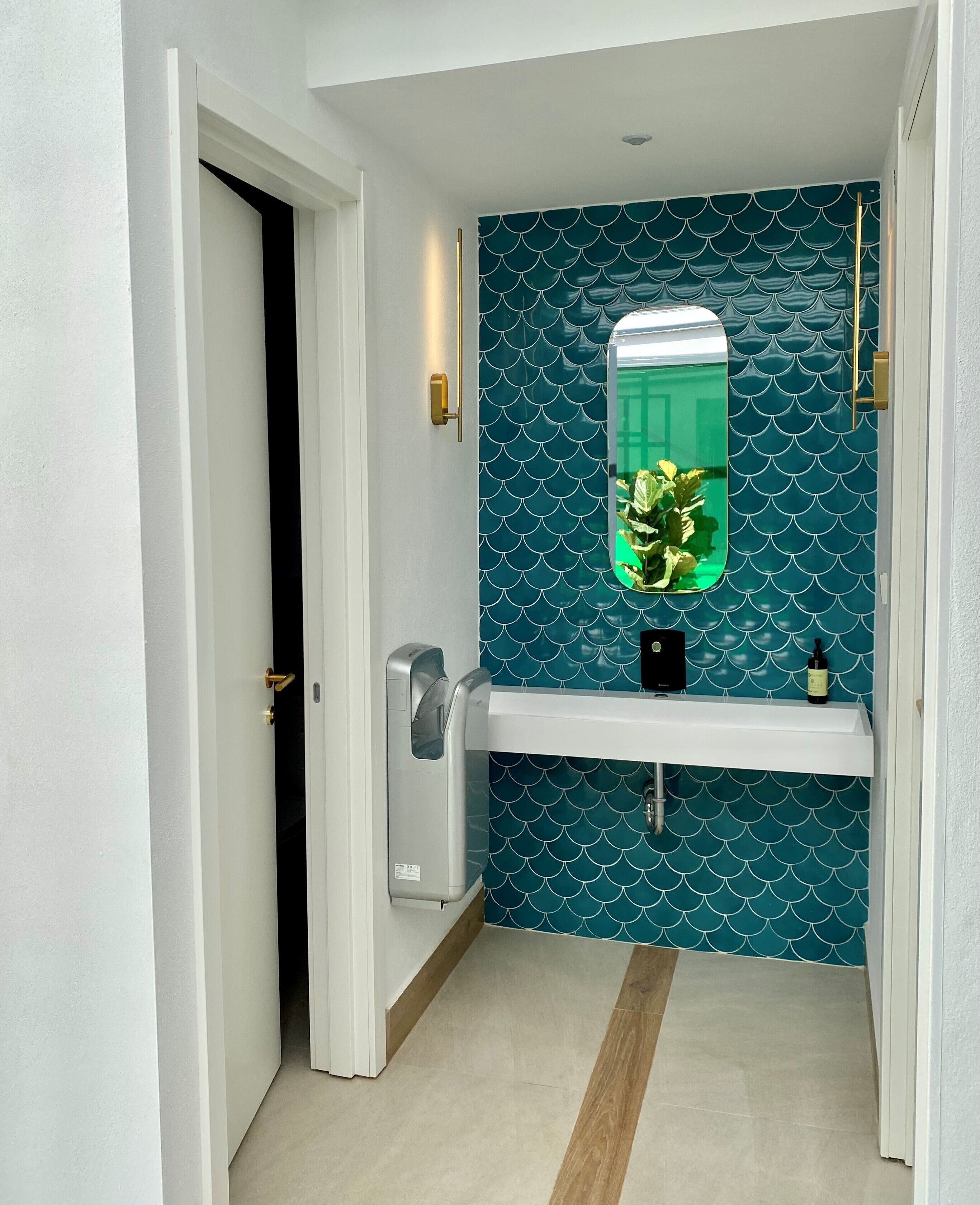 Um banheiro com pia branca, espelho e parede com padrão de azulejos azuis.