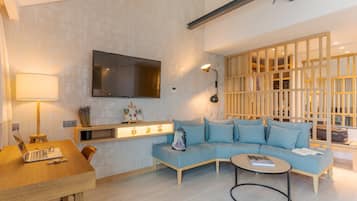 Uma sala de estar moderna com um sofá de madeira, uma TV na parede, uma escrivaninha com um laptop e um abajur.