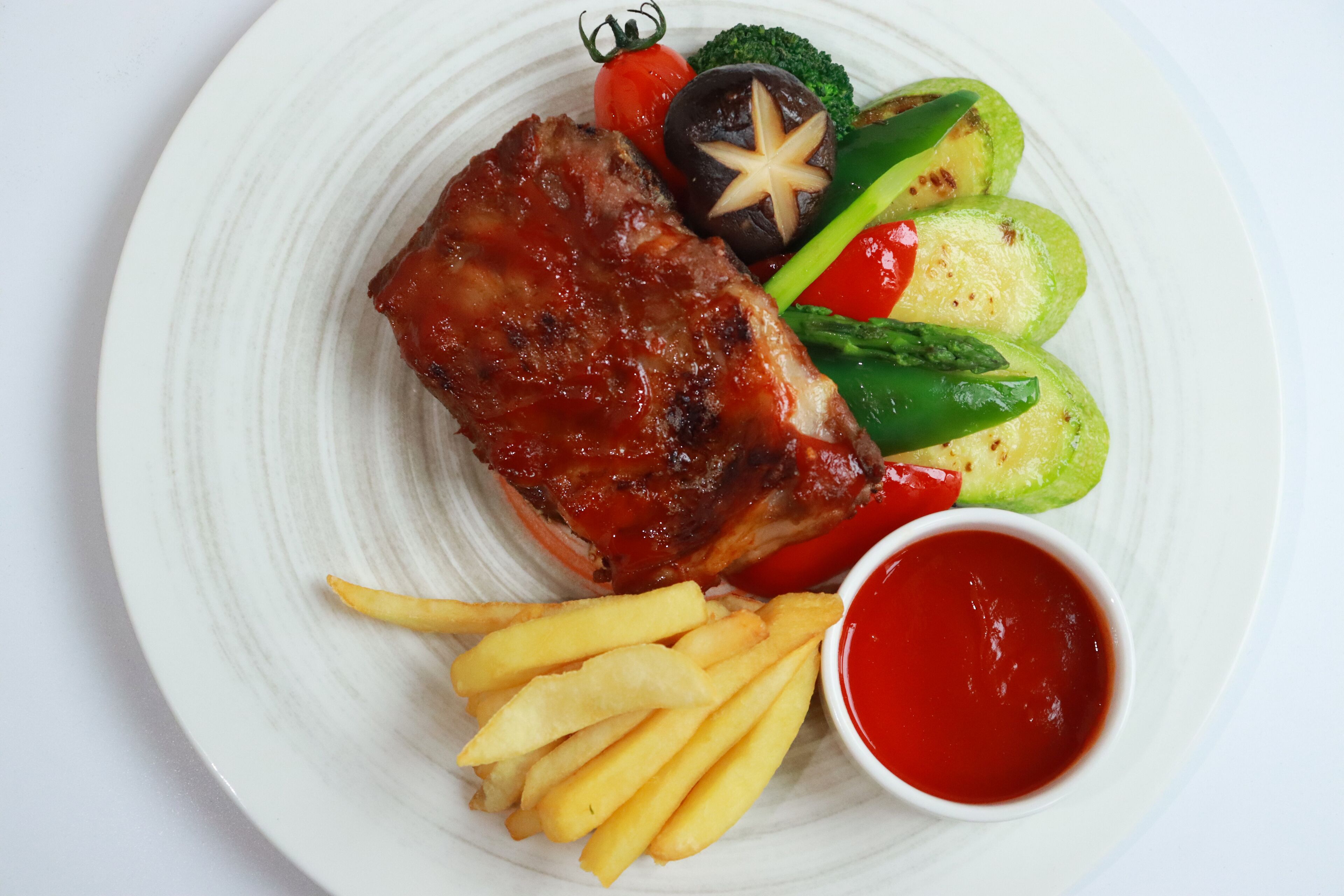Prato com costelas, legumes e batatas fritas.