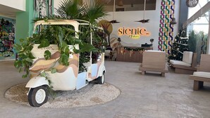 Carro vintage branco com plantas, um balcão de recepção e um pinheiro de Natal em um saguão.