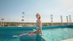 Uma pessoa sentada em uma piscina com vista clara da paisagem ao redor e uma estrutura de cerca.