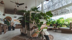 Uma scooter decorada com plantas em um espaço interno amplo, com assentos e uma grande janela.