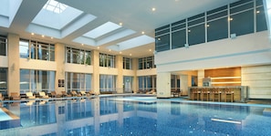 Uma grande piscina interior com vários níveis de assentos e uma área de recepção.